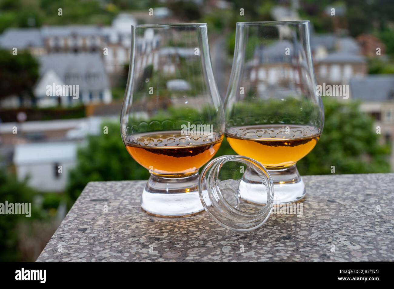 Two drams of scotch whiskey with view on old houses on background ...