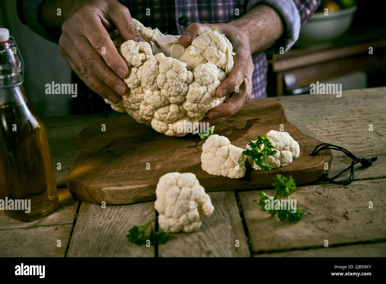 Crop man in checkered shirt tearing fresh cauliflower in pieces over ...