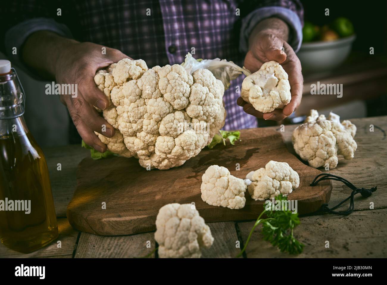 Anonymous male in checkered shirt dividing ripe cauliflower on smaller ...