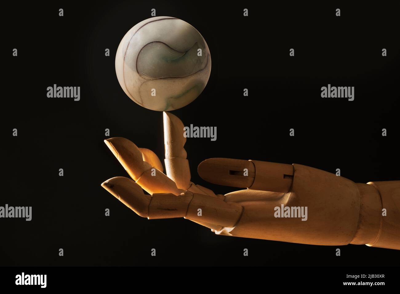 Wooden hand balancing a ball on fingertip Stock Photo - Alamy