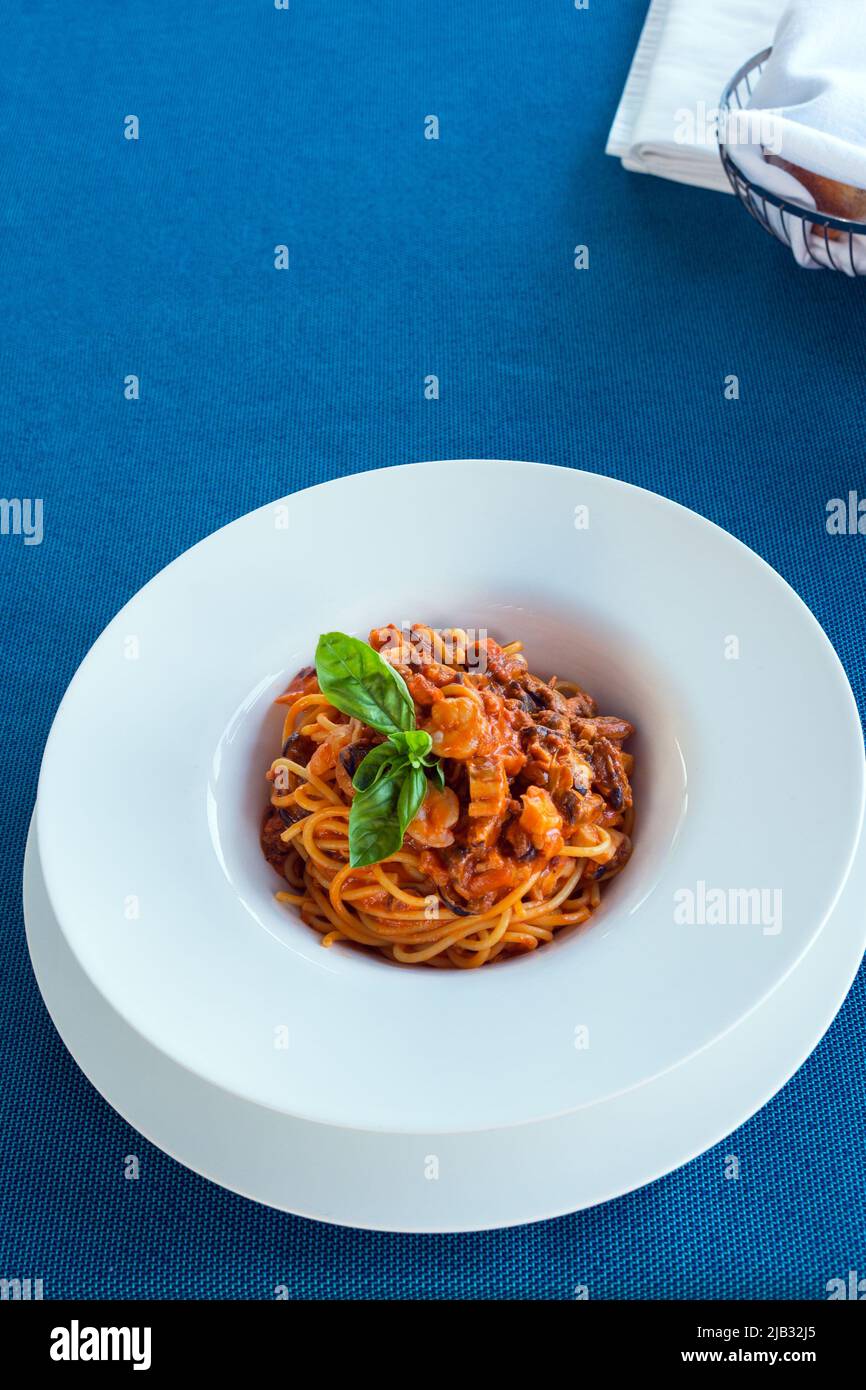 Delicious Italian pasta with seafood in tomato sauce in a white plate ...