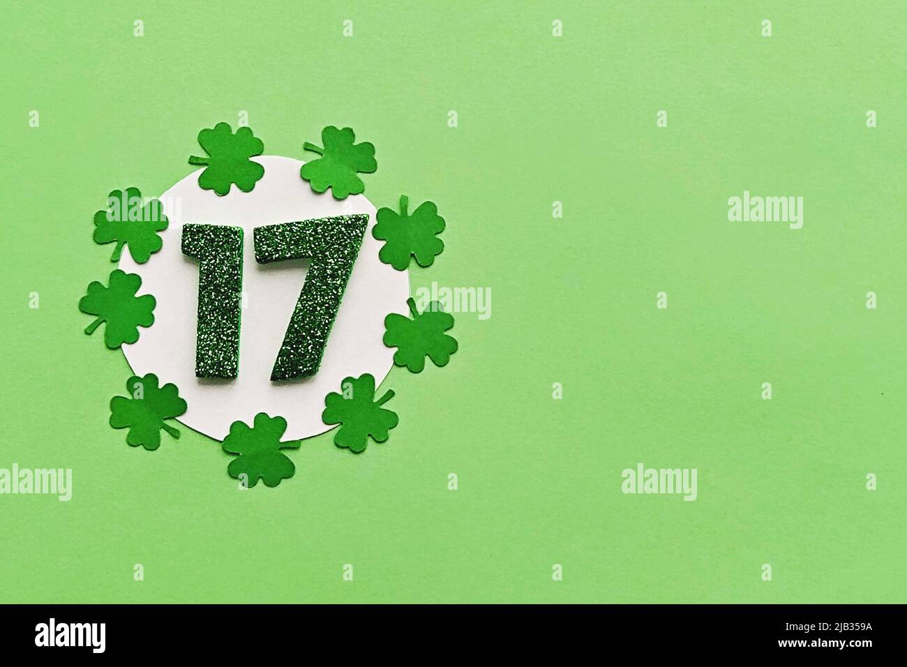 Numeral 17 on white background with frame of paper-cut four-leaf clover ...