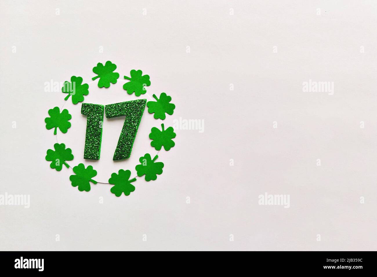 Numeral 17 on white background with round frame of paper-cut four-leaf ...