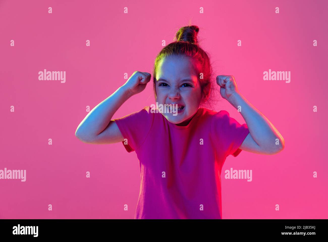 Portrait of angry little girl, kid wearing pink t-shirt posing isolated ...