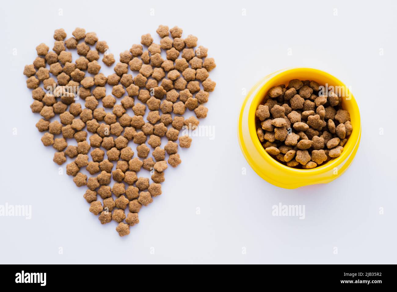 top view of dry pet food in shape of heart and bowl isolated on white ...