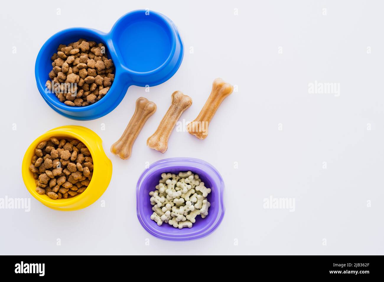 top view of bone shaped pet treats near bowls with water and dry pet ...
