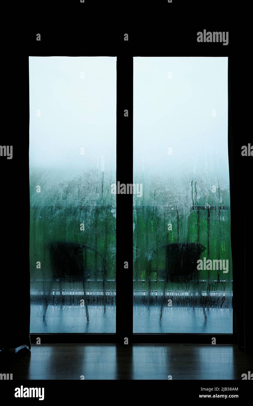 Dark frame of glass windows wet by rain with blurry background of ...
