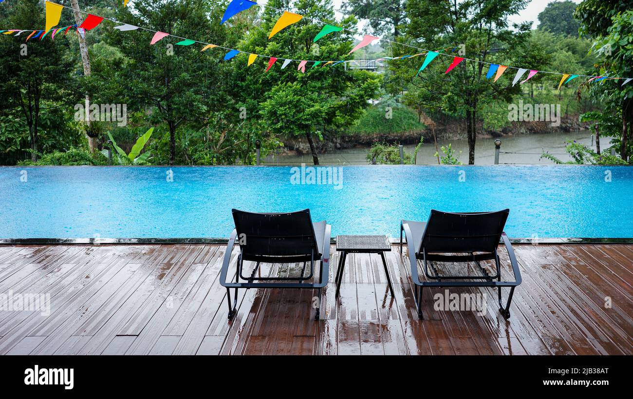 Swimming pool and beach benches on wet wooden terrace after raining ...