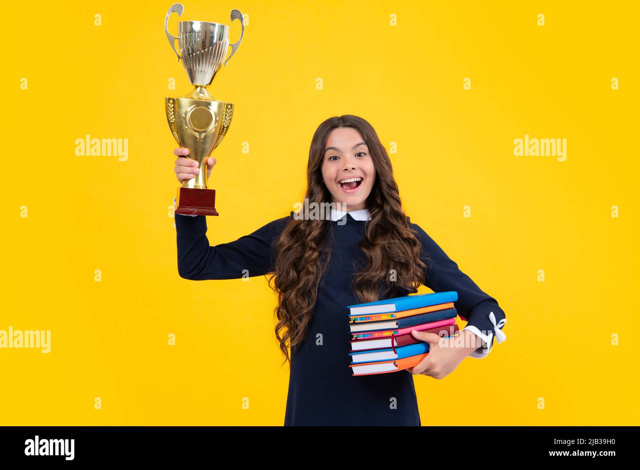 Excited schoolgirl in school uniform celebrating victory with trophy ...