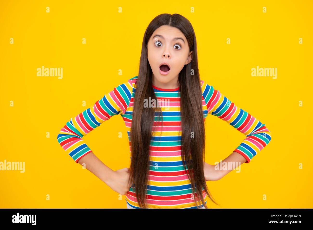Surprised teenager girl. Shocked teenager child portrait isolated on yellow background ...