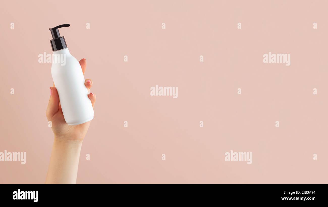 A mockup of a white dispenser with a cosmetic product in a woman's hand ...