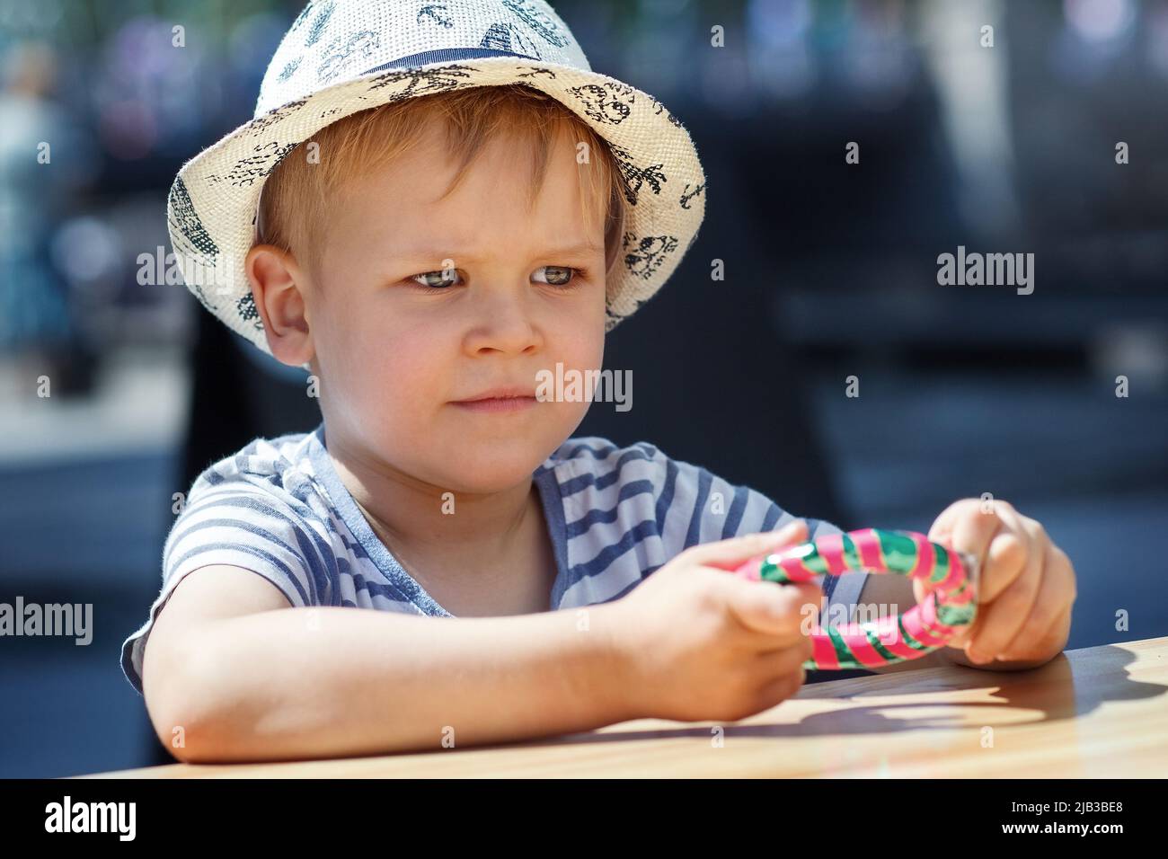 A portrait of a little boy holding a bracelet-shaped candy in his hands ...