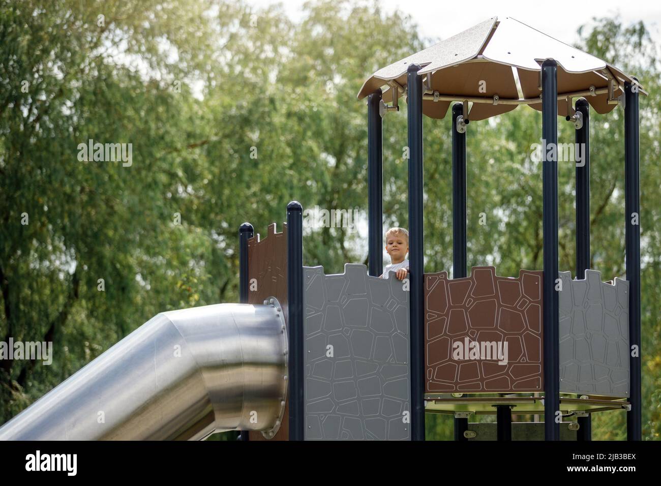 A little boy in the high observation tower of the playground prepares ...