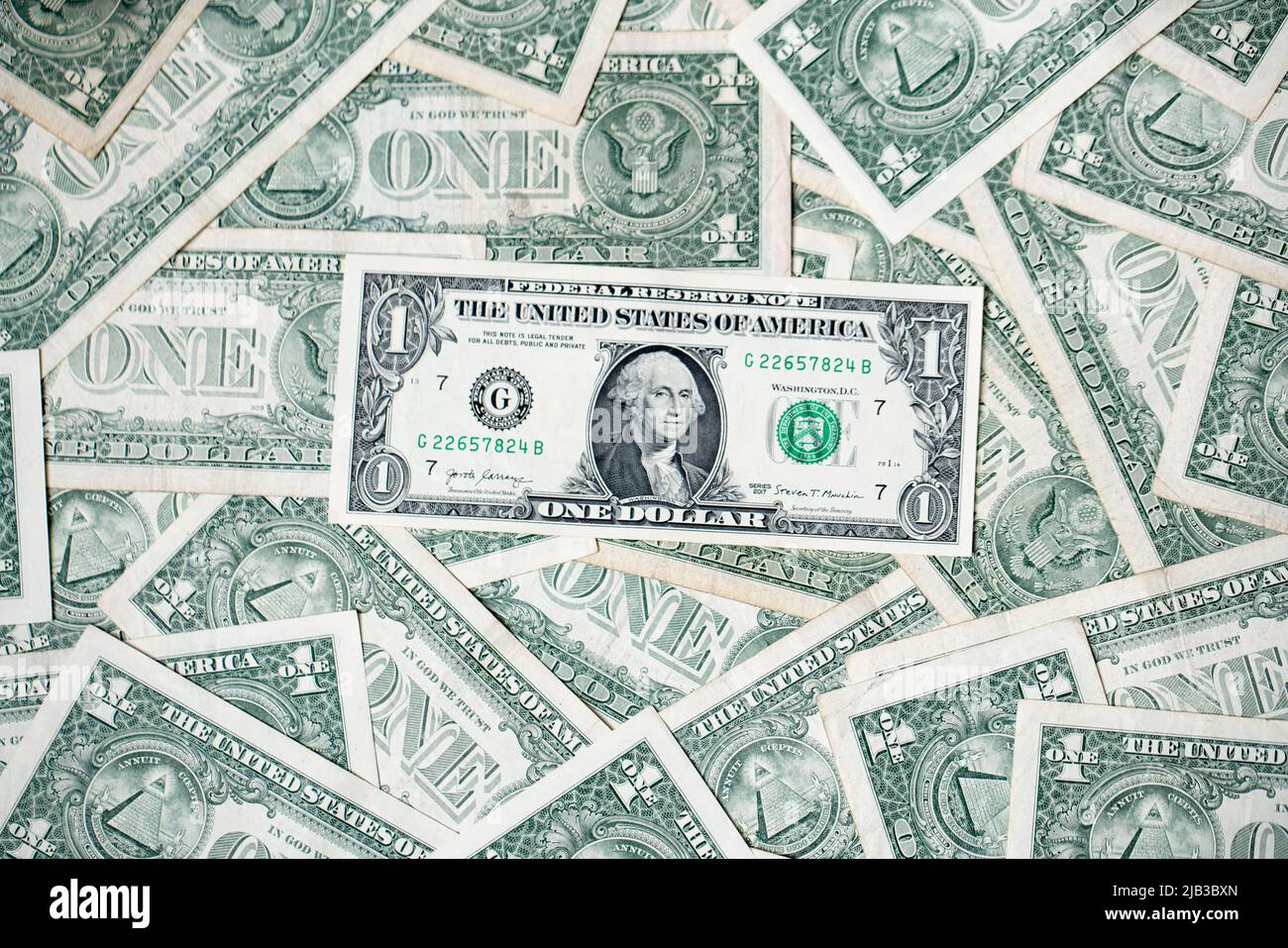 One dollar banknote on top of spread out dollar bills on the back side ...