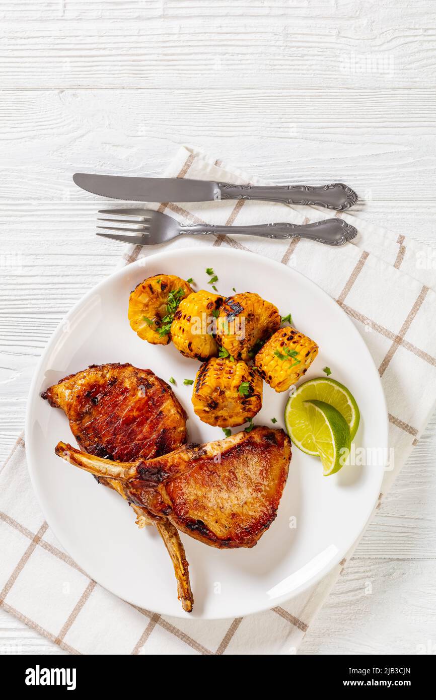 roasted tomahawk pork chops, bone-in steak with grilled corn disks and ...