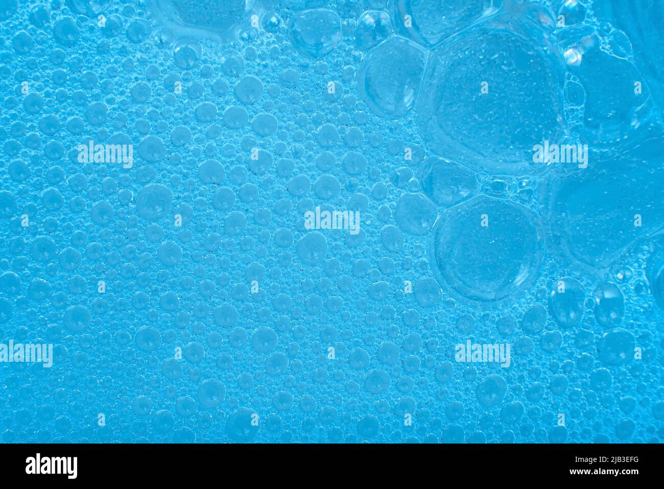 Soap foam in blue close-up. Foam bubbles on the surface of detergent or ...