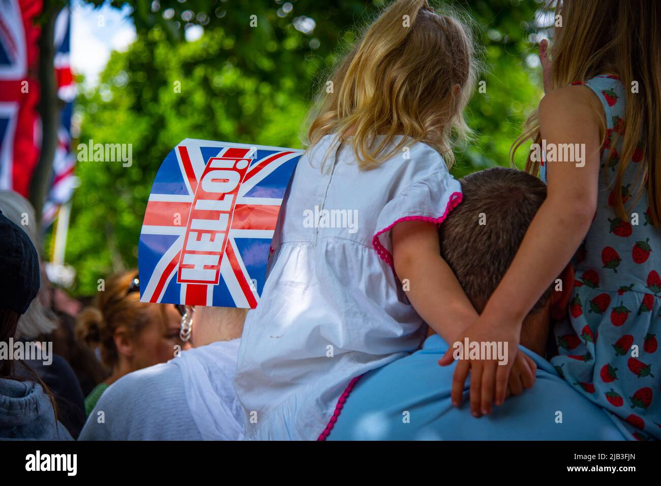 Young fans view the parade while holding a Hello! flag during the Queen ...