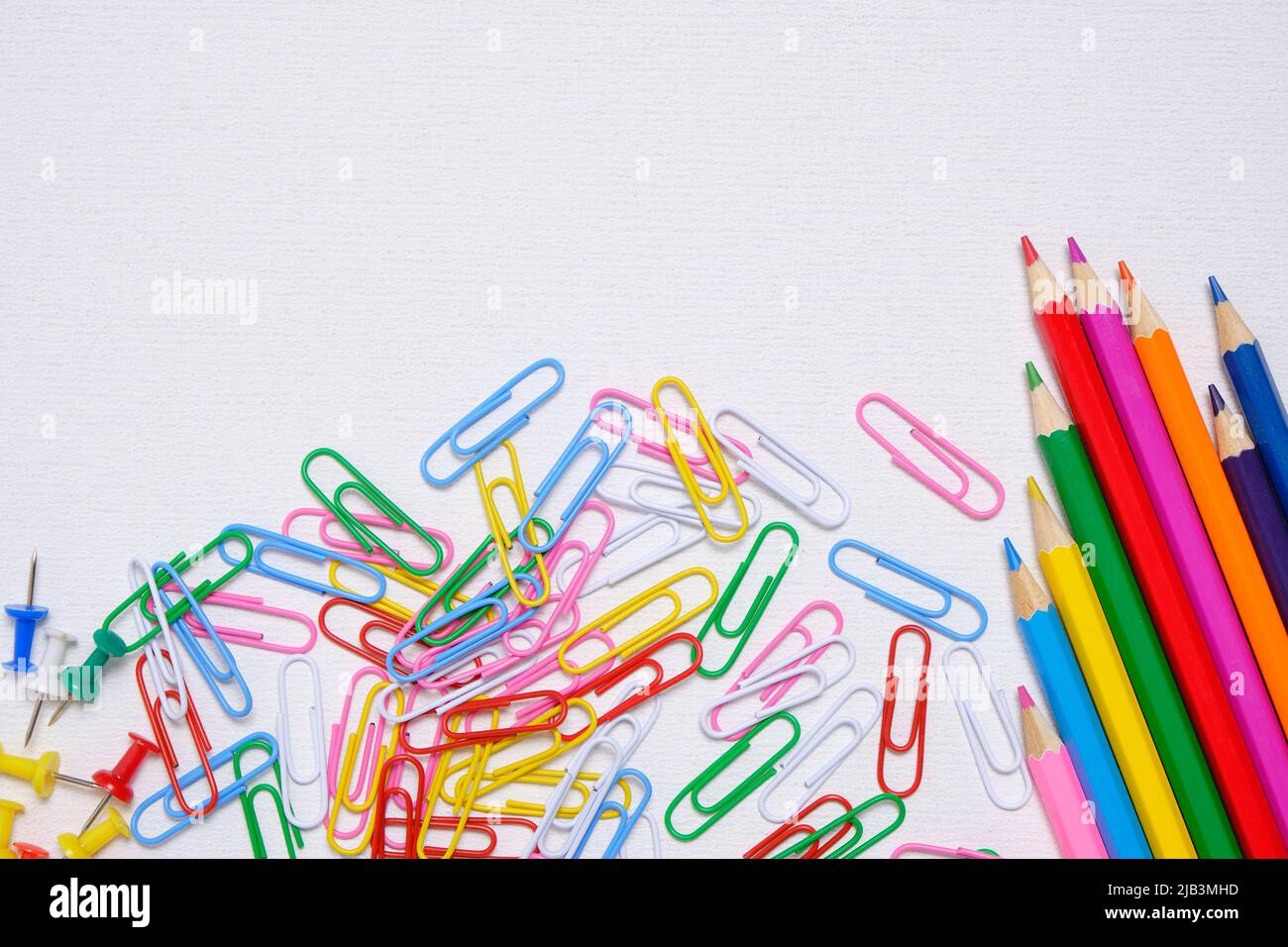 Colored pencils and paper clips white background, school supplies and ...