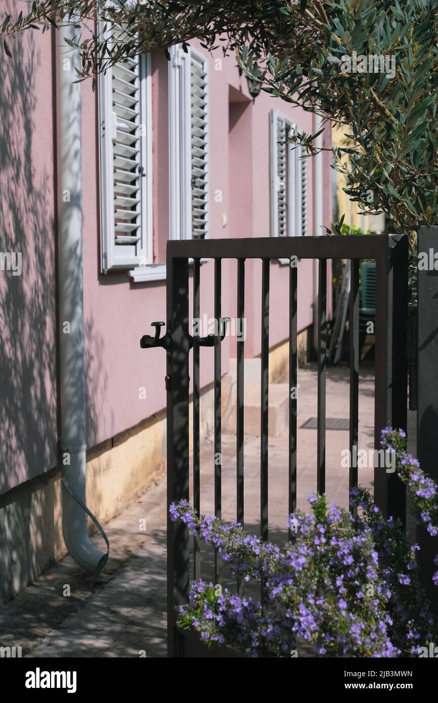 open gate with flowers on pink house wall with white shutters ...