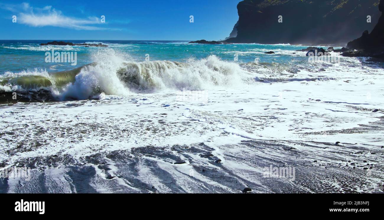 Beautiful secluded black lava sand beach bay, rocks, big strong ...