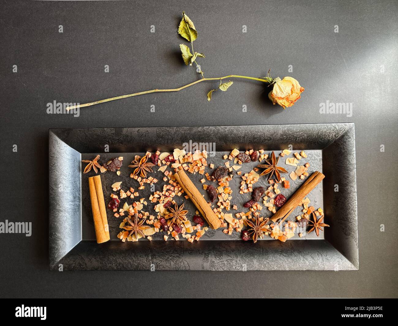 A mixture of dried fruits and spices lies on a black tray next to a dry ...