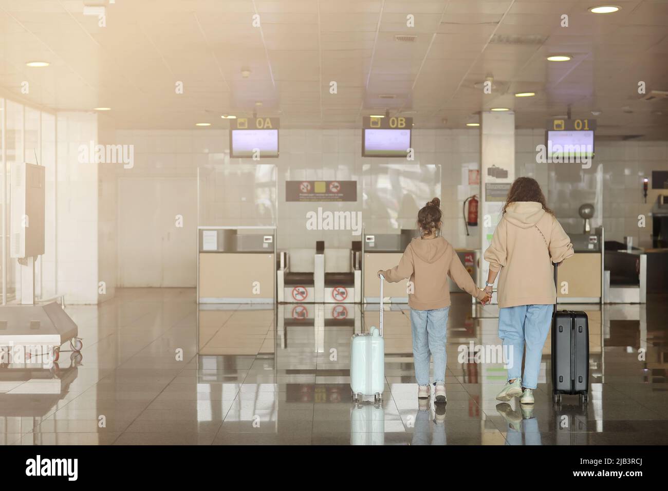 Family at airport before flight. back view of mother with daughter with ...