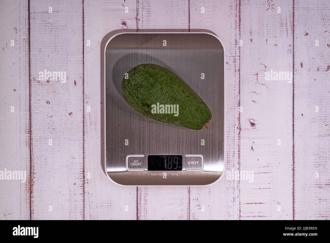An avocado lies on a digital kitchen scale on a table of light boards ...