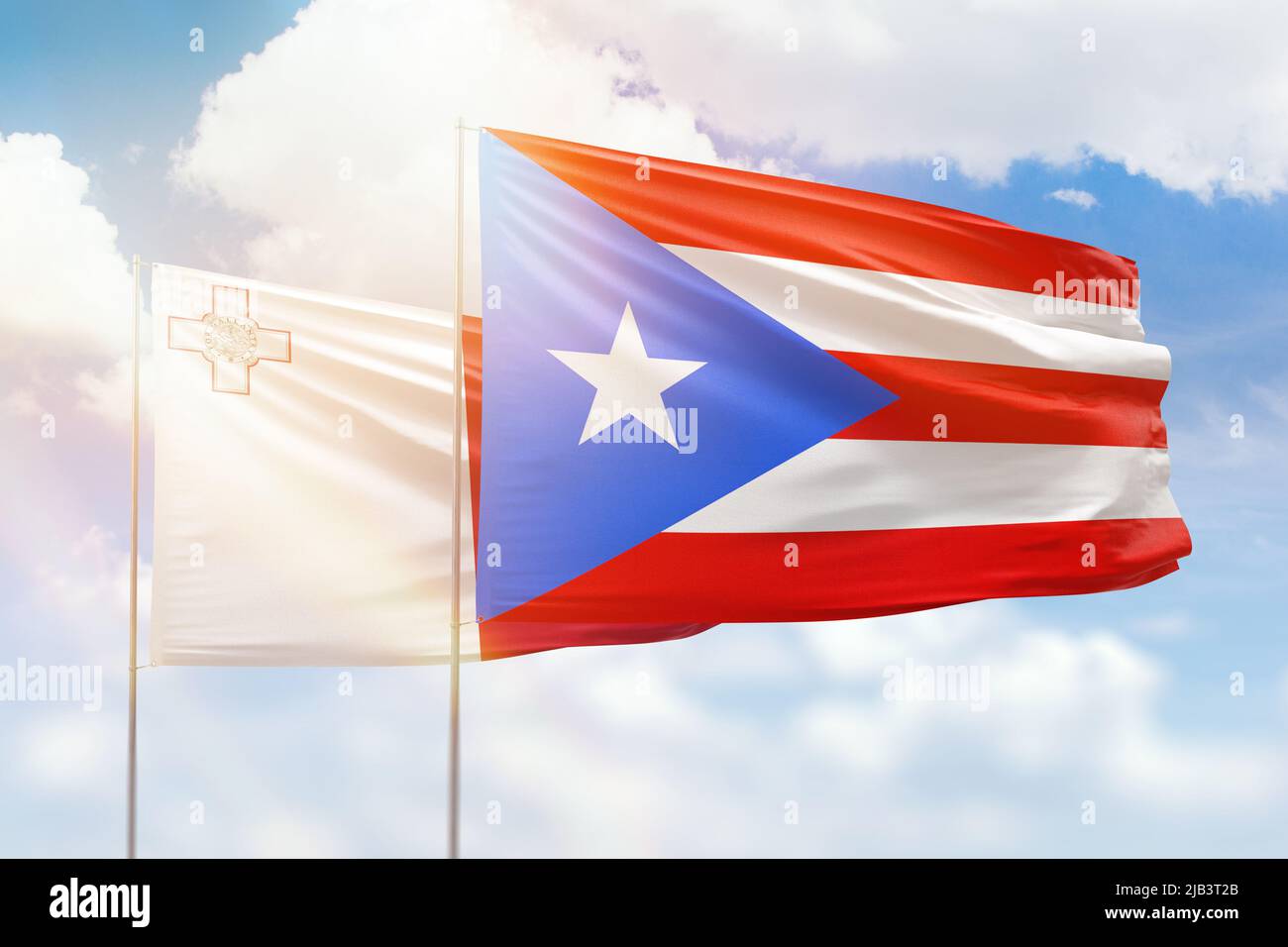 Sunny blue sky and flags of puerto rico and malta Stock Photo - Alamy