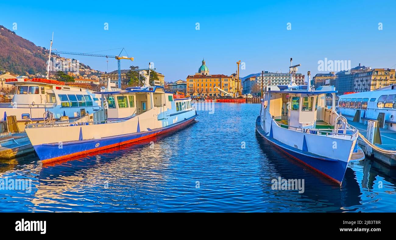 Walk by the Lake Como with a view of ferries in port and old town ...