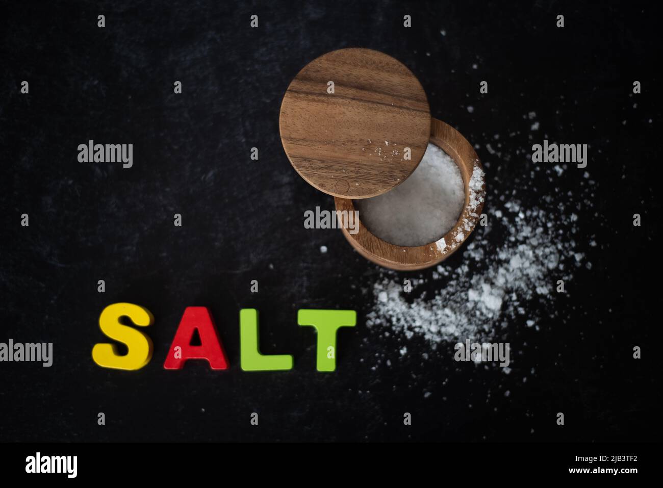 Top view of sea salt in wooden container on dark moody background with ...