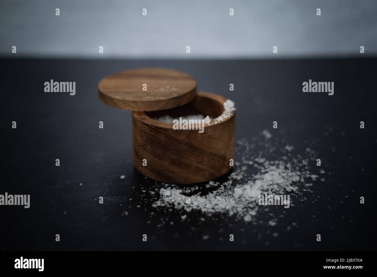 Side view of sea salt on dark moody background inside wooden salt ...