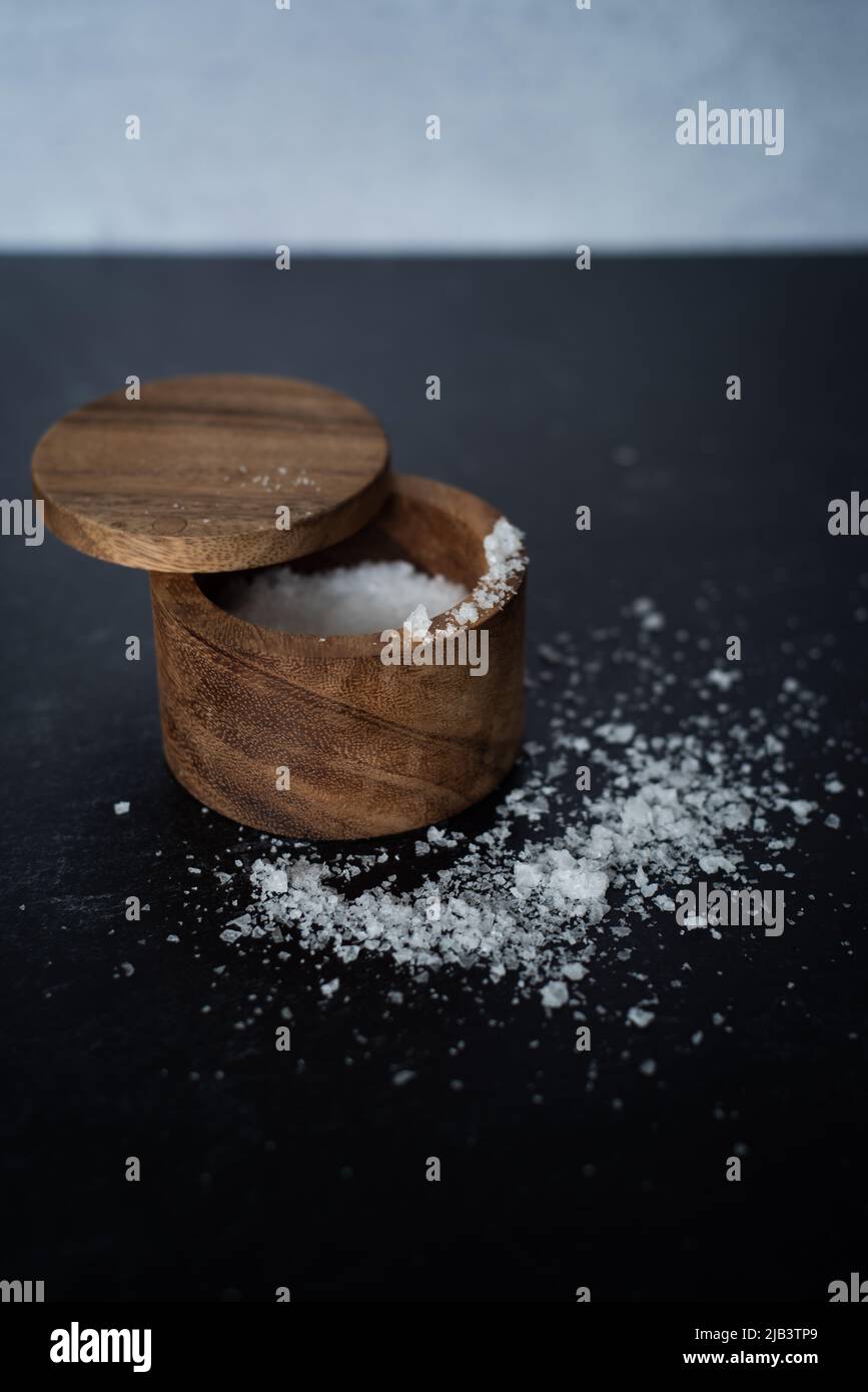Side portrait view of sea salt on dark moody background inside wooden ...