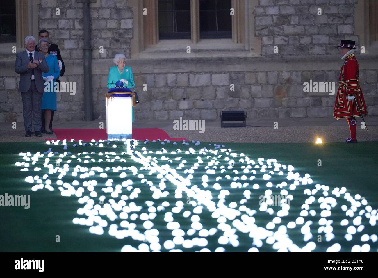 Queen Elizabeth II symbolically leads the lighting of the principal ...