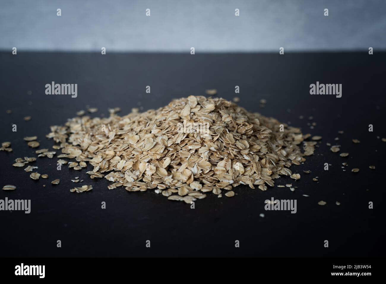 Closeup side top view of organic oats in a pile on dark moody ...