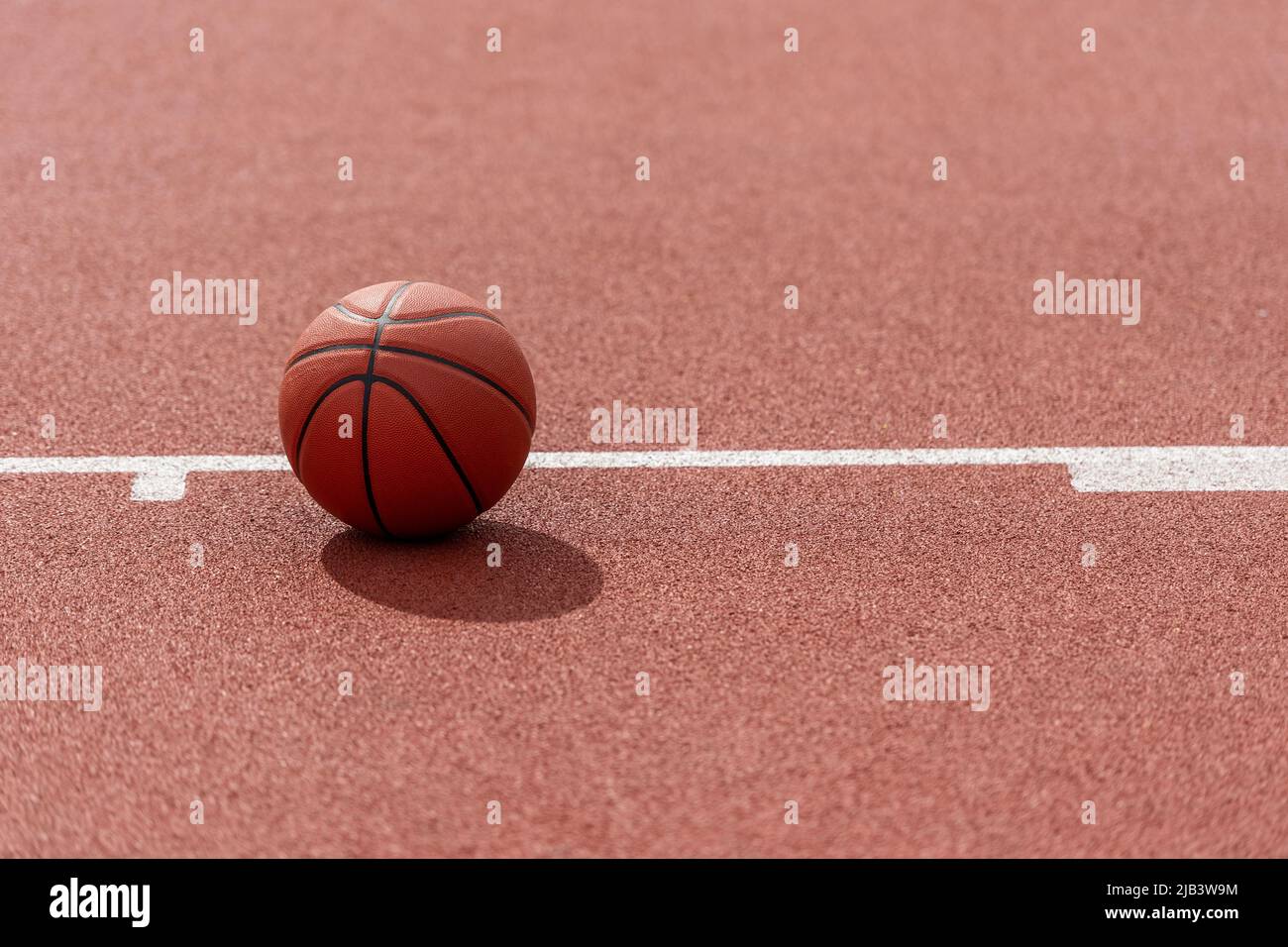 Orange basketball on red court of gymnasium sport floor. Street ...