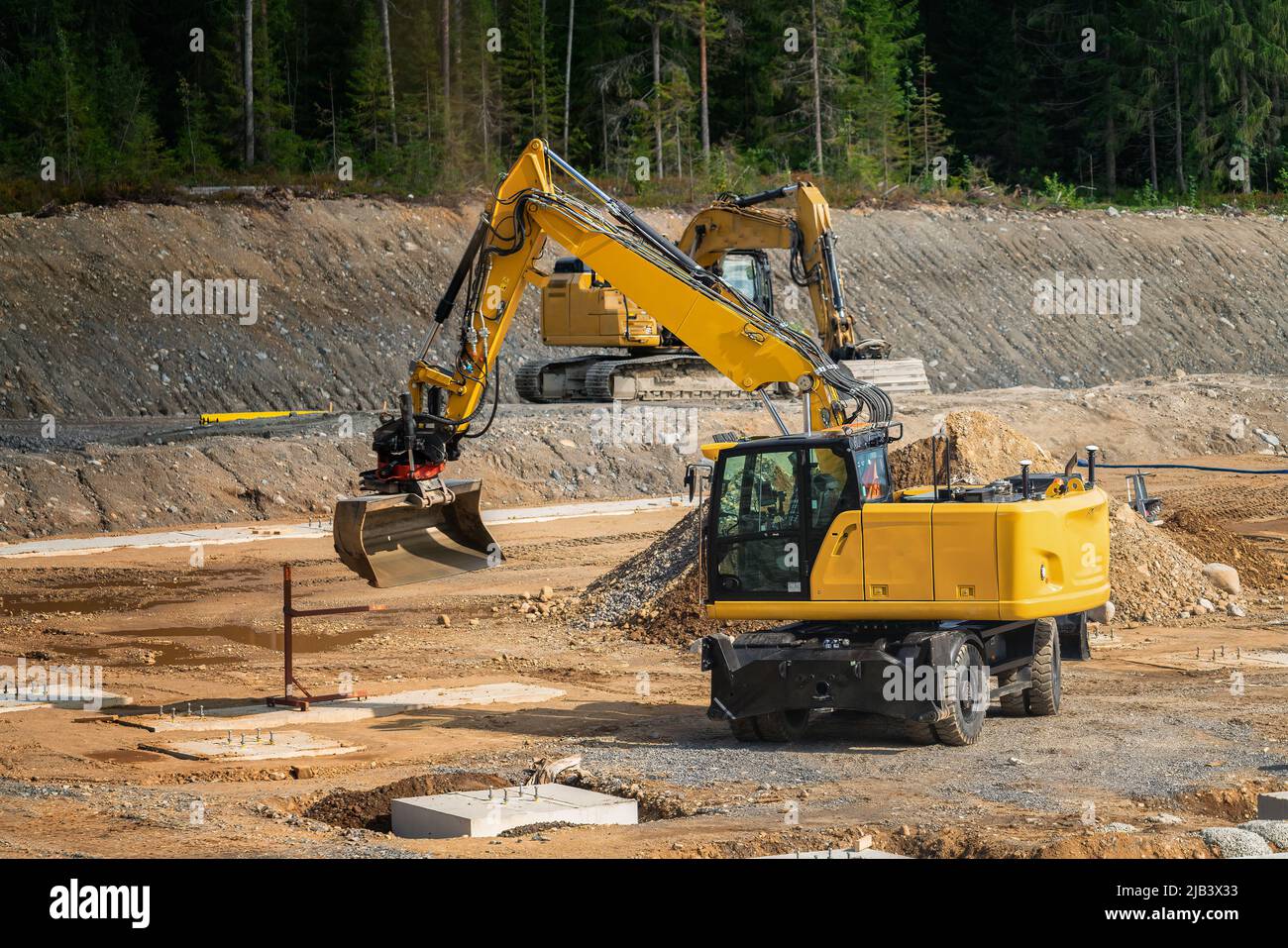 Two excavators at work - prepare ground for concrete foundations on the site of a new building ...