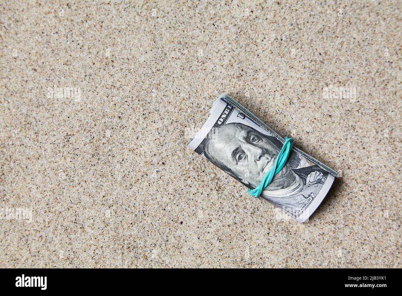 Roll of dollars lost in the sand. Left on the beach Stock Photo - Alamy
