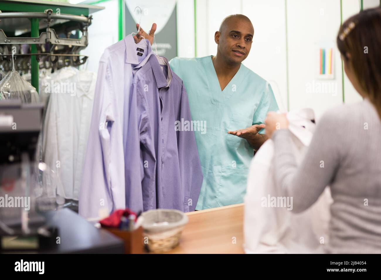 Man dry-cleaning worker giving clothes to customer Stock Photo - Alamy
