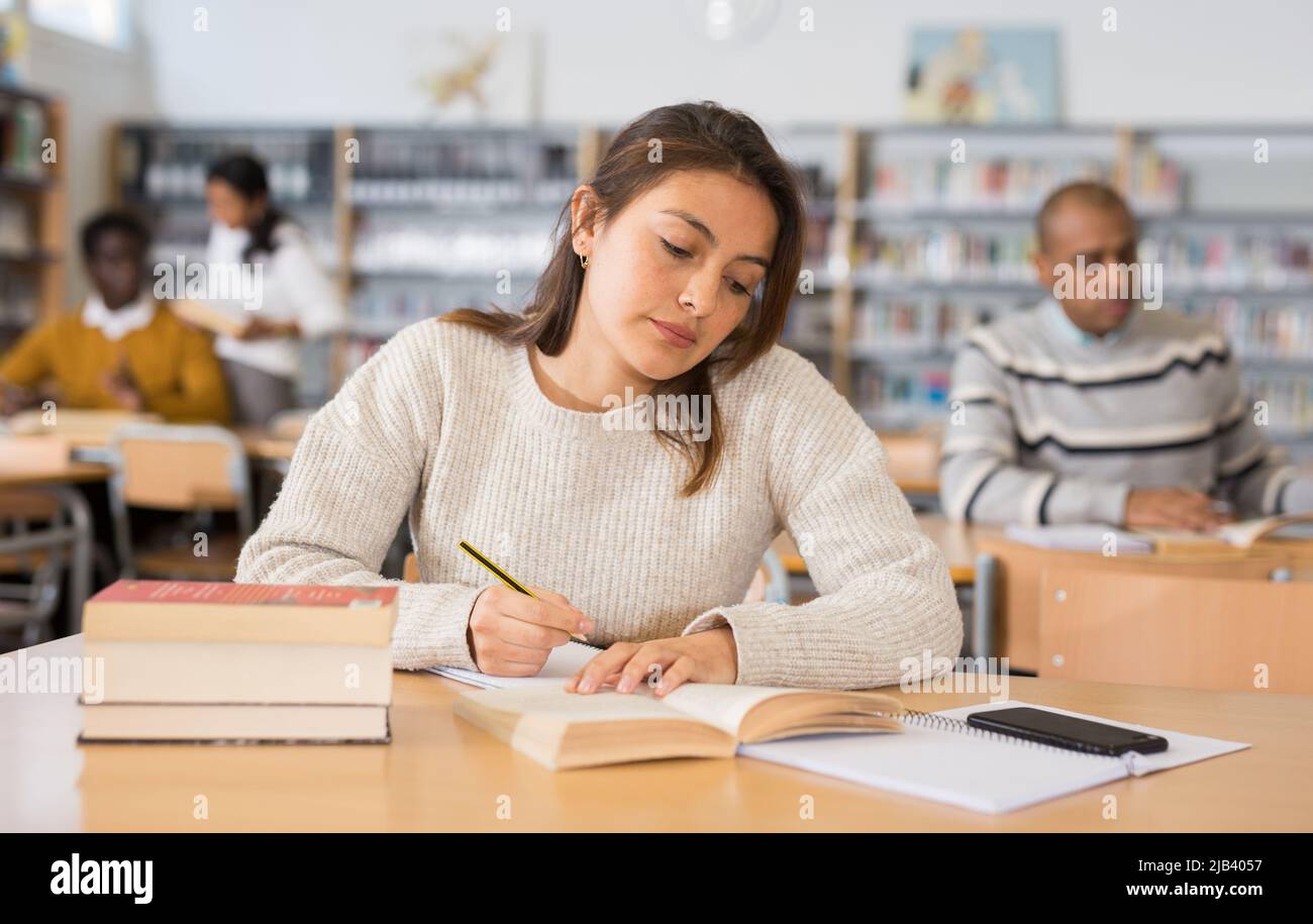 Young adult woman studying in public library Stock Photo - Alamy