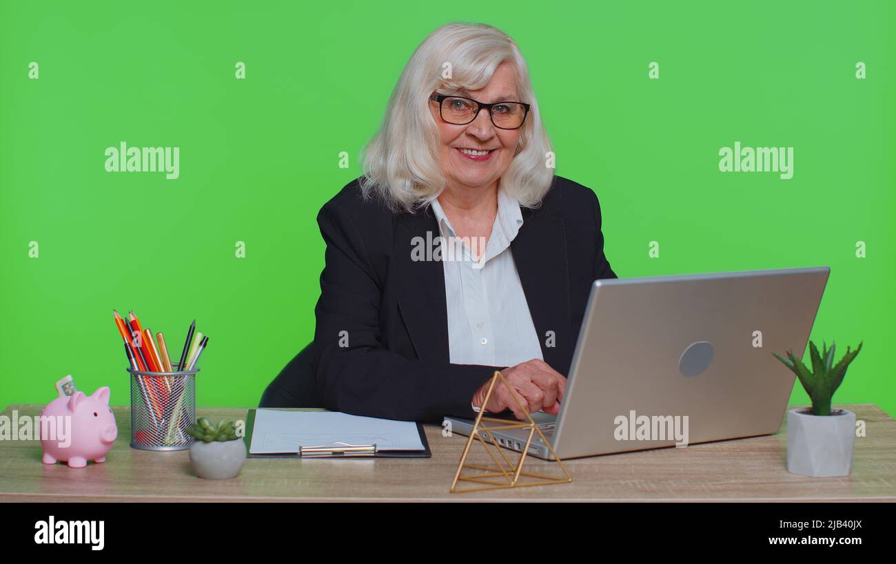 Smiling professional mature business woman opening laptop computer at ...