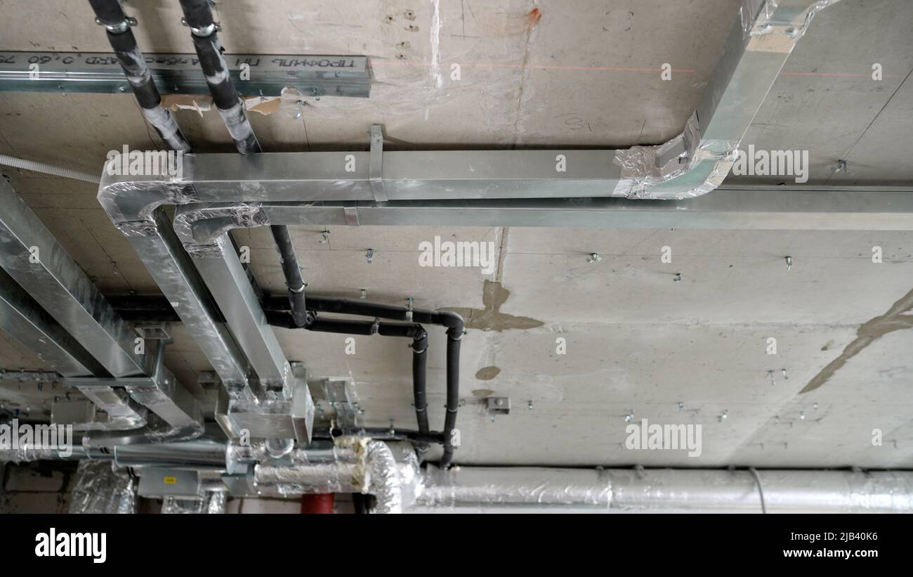 Ceiling in a new apartment with a system of ventilation pipes and wires ...