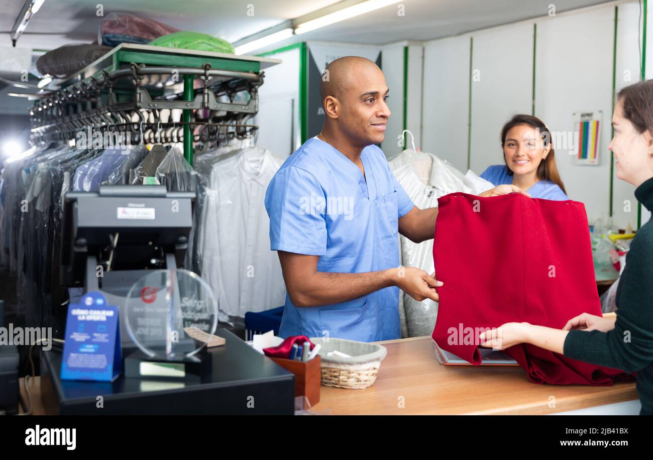 Man dry-cleaning worker giving clothes to customer Stock Photo - Alamy