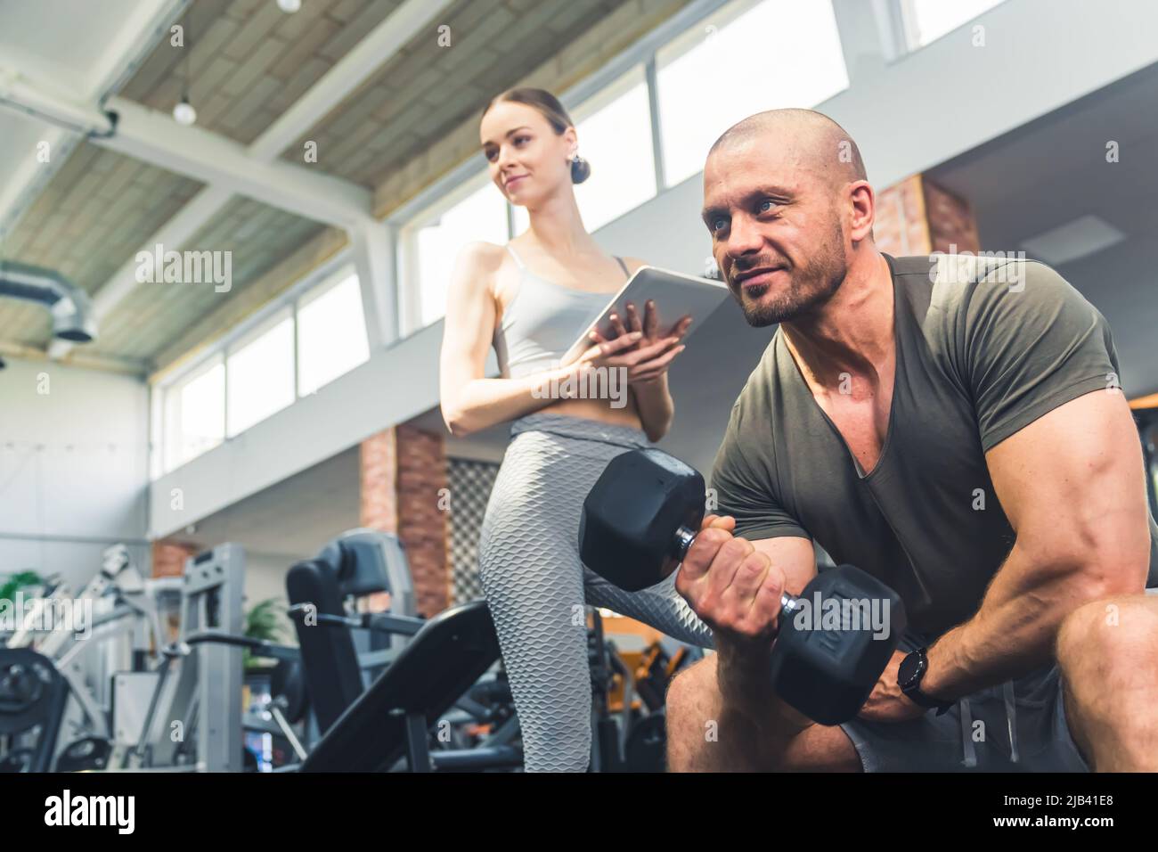 Female attractive slim personal trainer coordinating a weight training ...