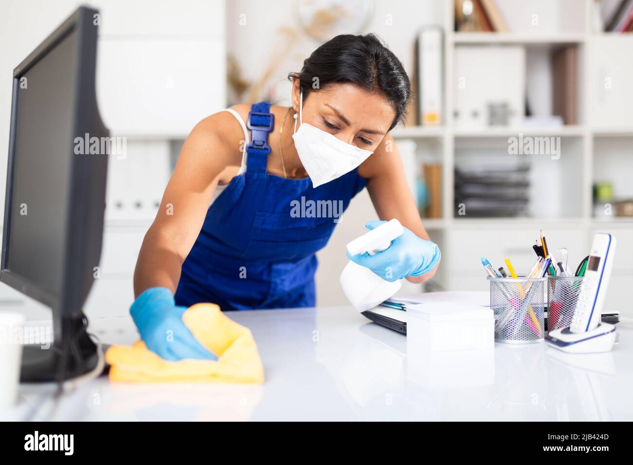 Professional cleaning woman in mask and gloves wiping desk Stock Photo ...
