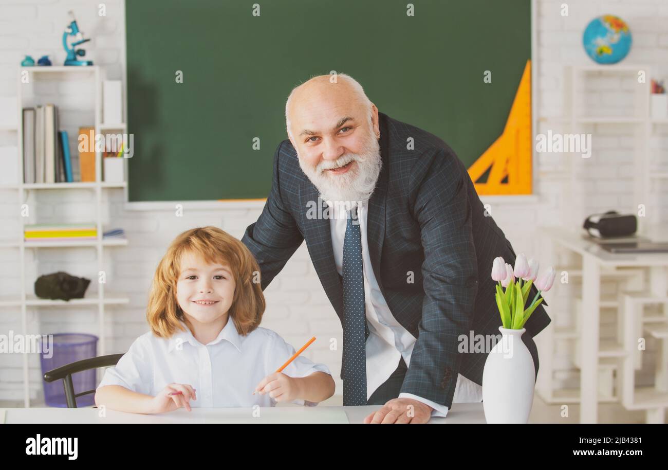 Old senior teacher and young student or school boy. Pupil learning to ...