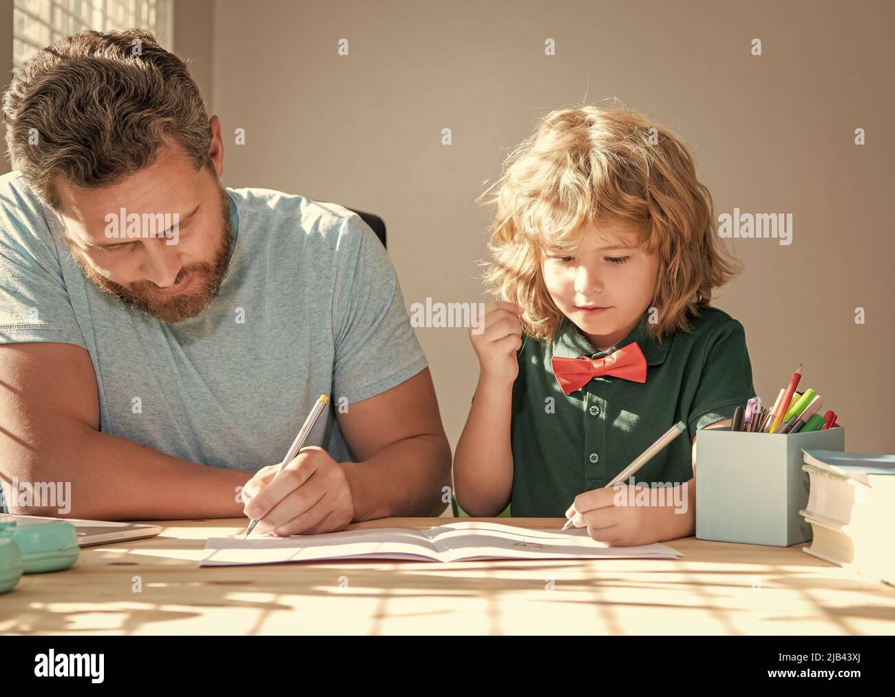 bearded father writing school homework with his kid son in classroom ...