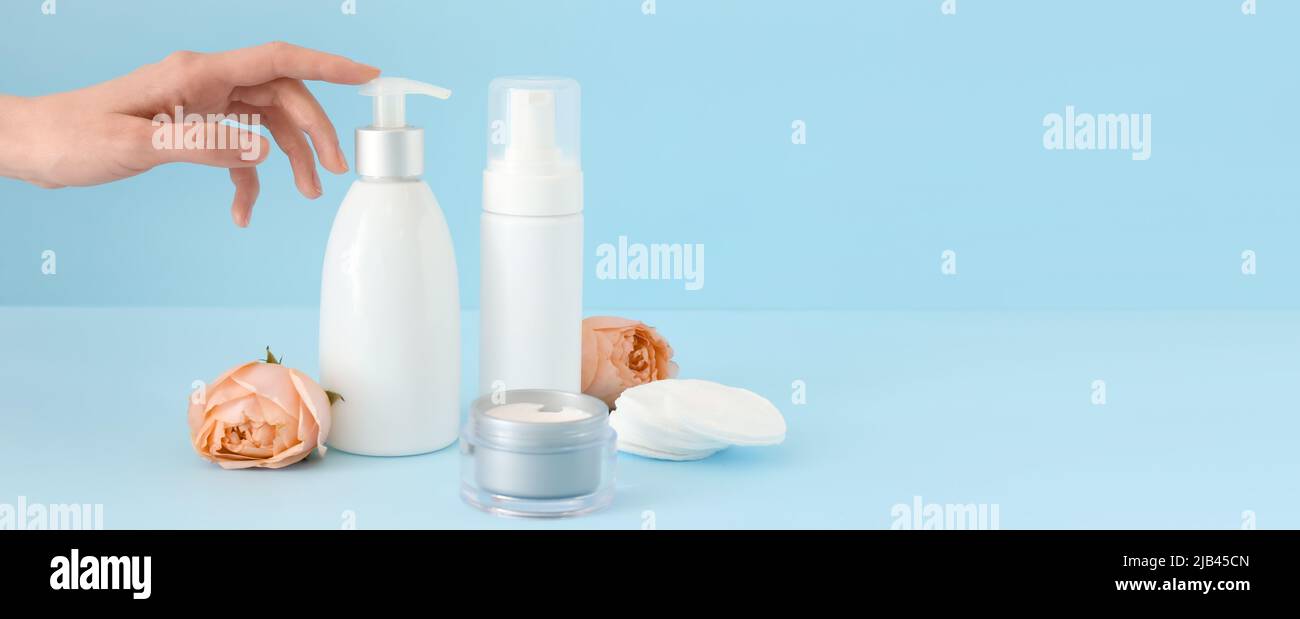 Female hand touching cosmetic products on light blue background with ...