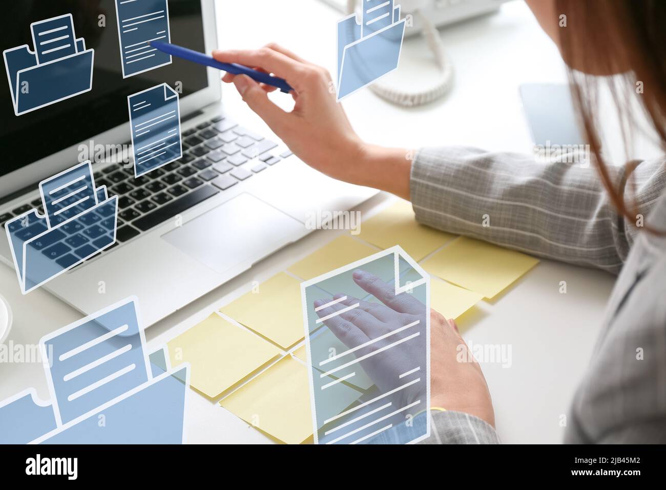 Young businesswoman with sticky note papers, laptop and digital files ...