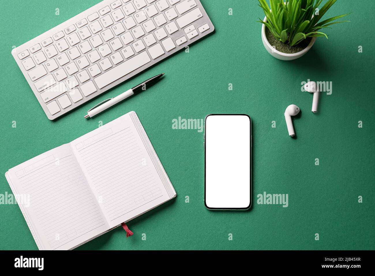 Mobile phone, notebook, earphones, pen and keyboard on color background ...