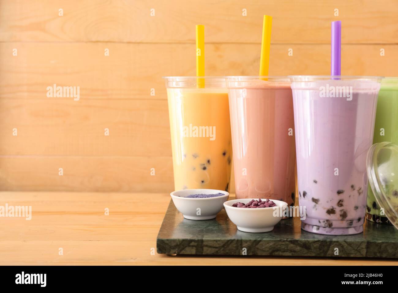 Board with plastic cups of different tasty bubble tea on table Stock ...